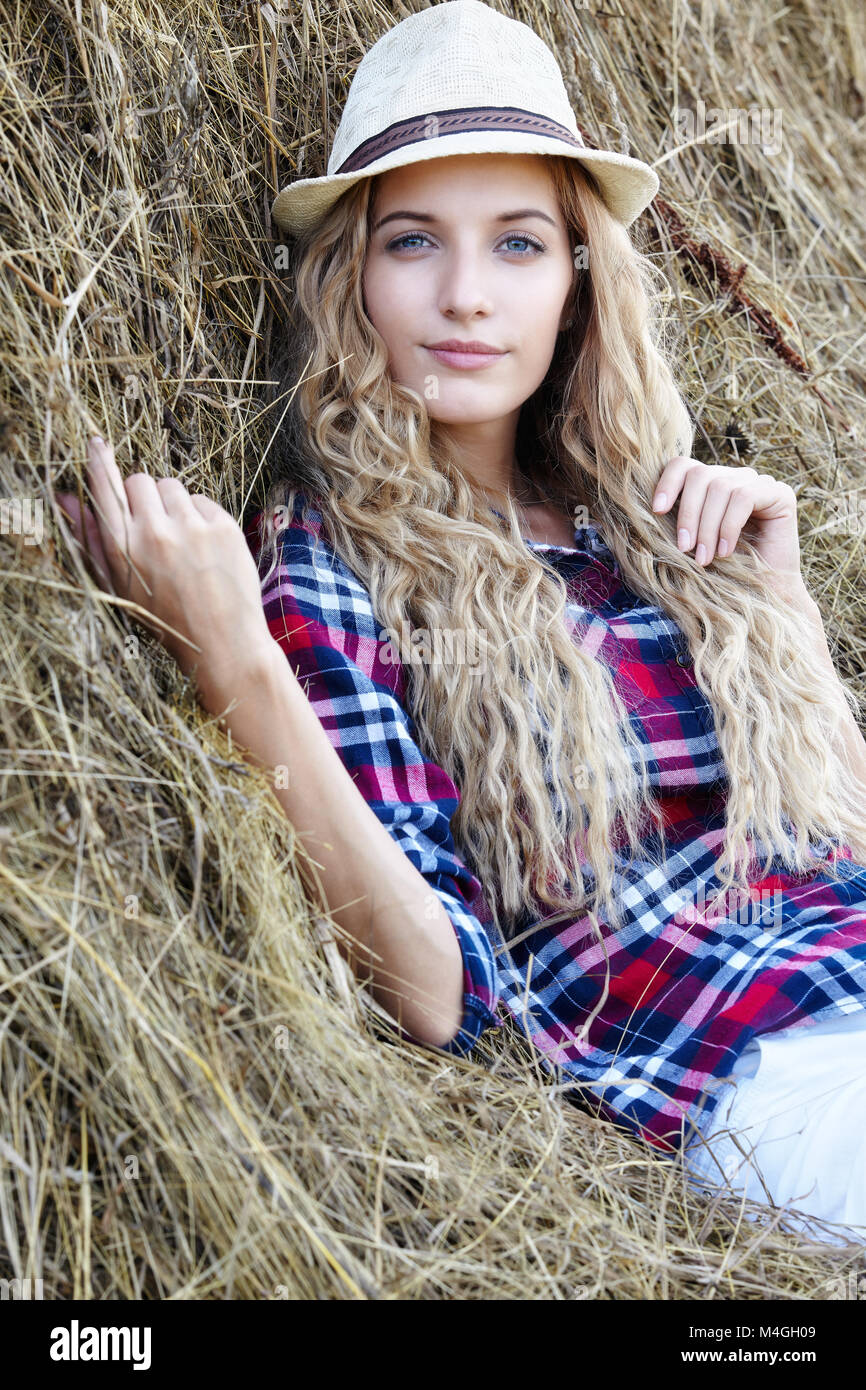 Young blonde country girl in hat sit near haystacks Stock Photo - Alamy