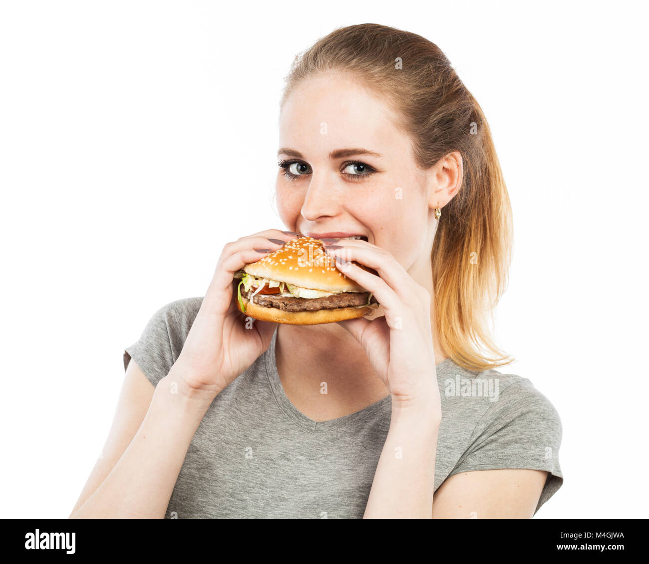 Portrait of a cute young woman biting into a burger, isolated on white ...