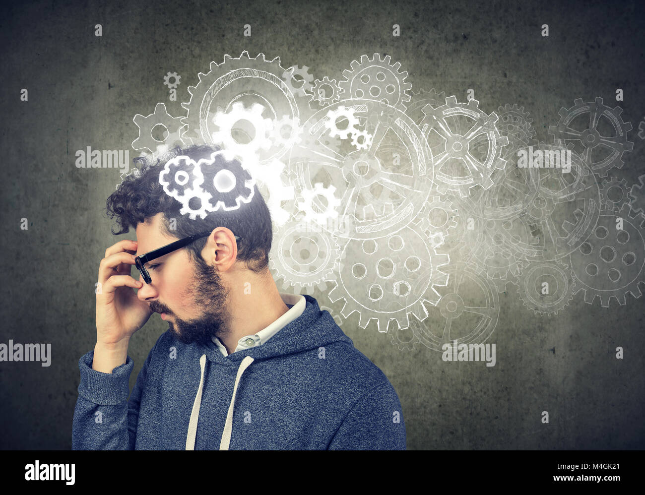 Thoughtful young man looking for a solution with gear mechanisms over ...