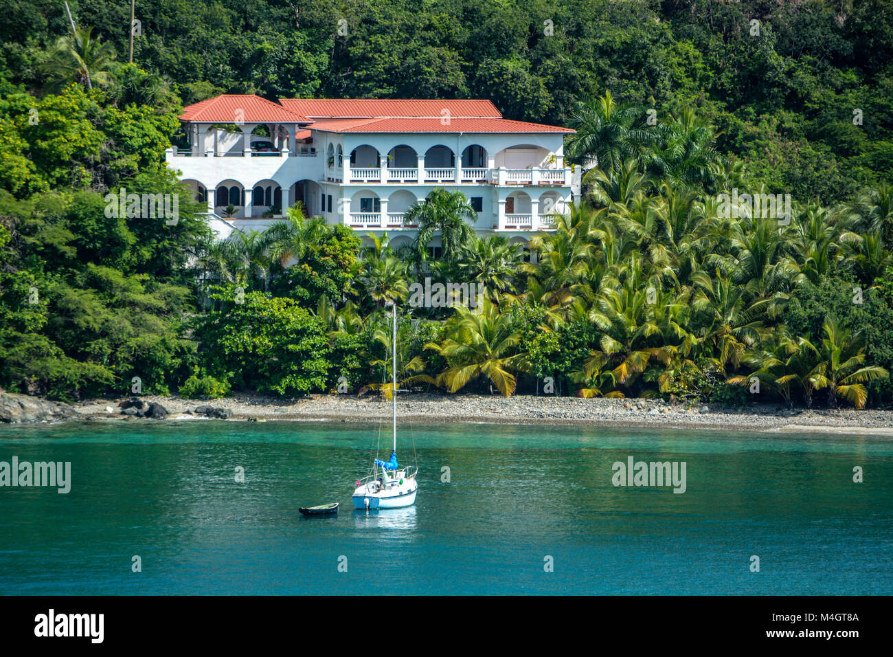 Tropical mansion overlooking sailboat in the cove Stock Photo - Alamy