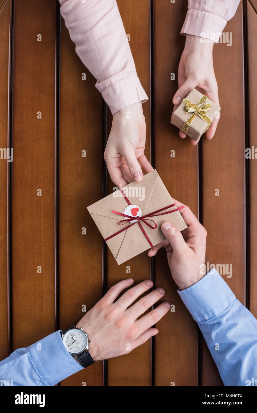 cropped image of girlfriend gifting postcard in envelope and present ...