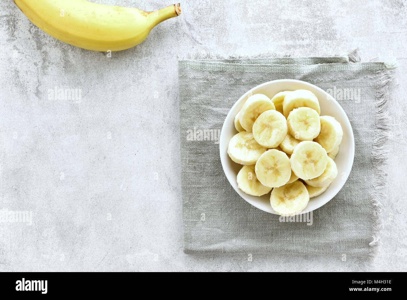 Sliced ripe banana in bowl on stone background with copy space. Healthy ...