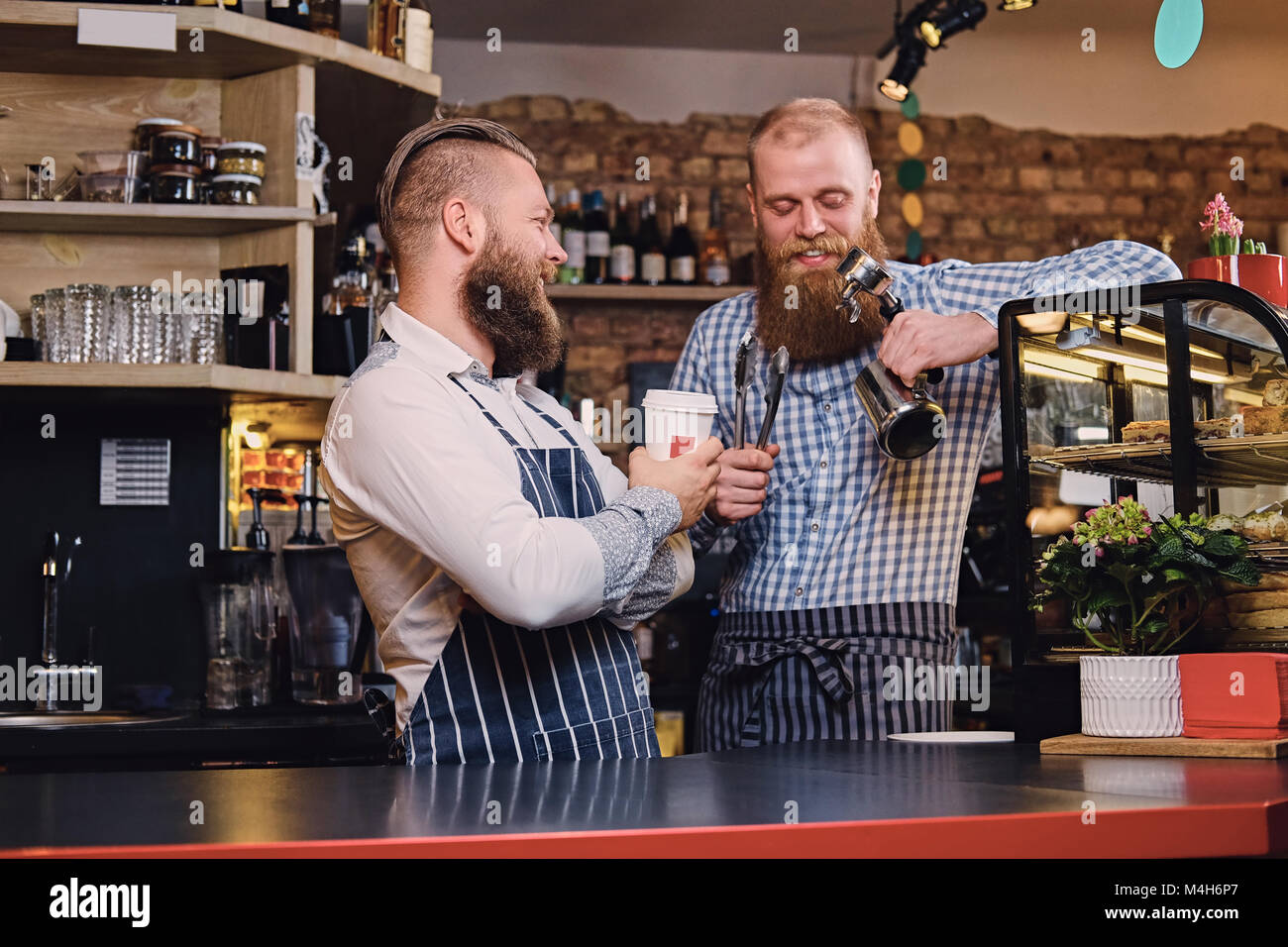 Two bearded hipster coffee shop owners at the counter. Positive redhead ...