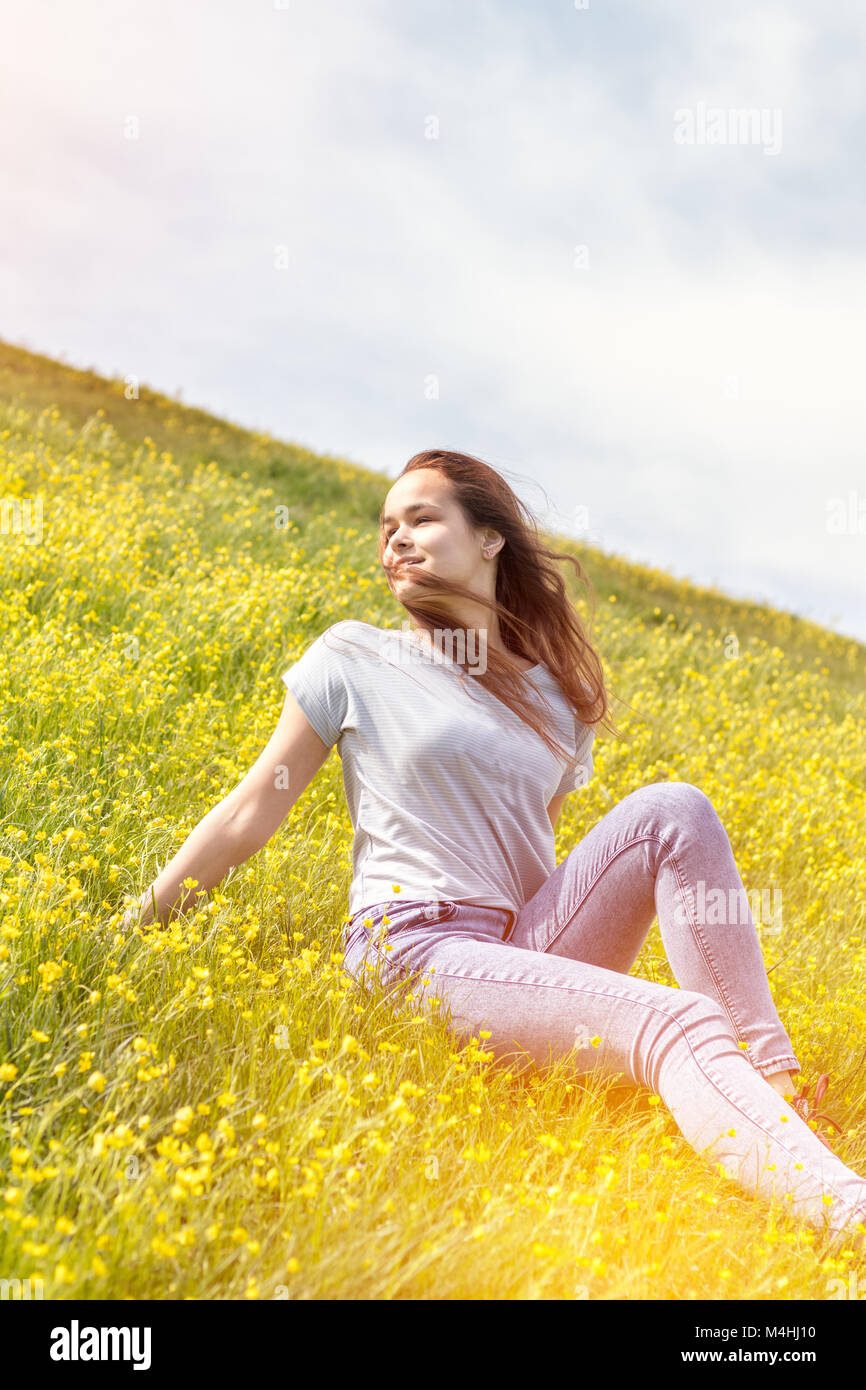 Young girl on a lawn field with yellow flowers Stock Photo - Alamy