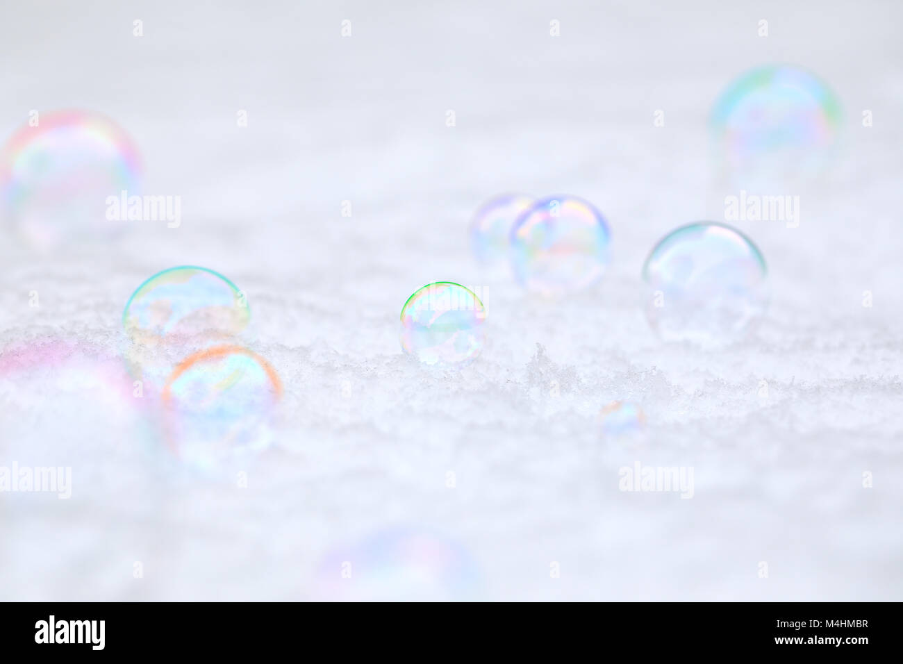 Bubbles in the snow with a rainbow of colors and iridescent and ...