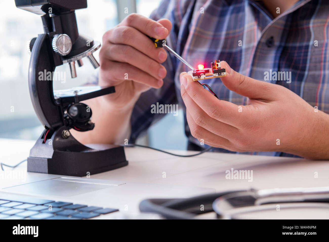 High precision engineering with man working with microscope Stock Photo ...