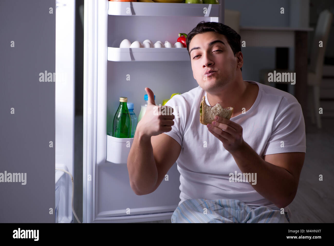 Man at the fridge eating at night Stock Photo - Alamy