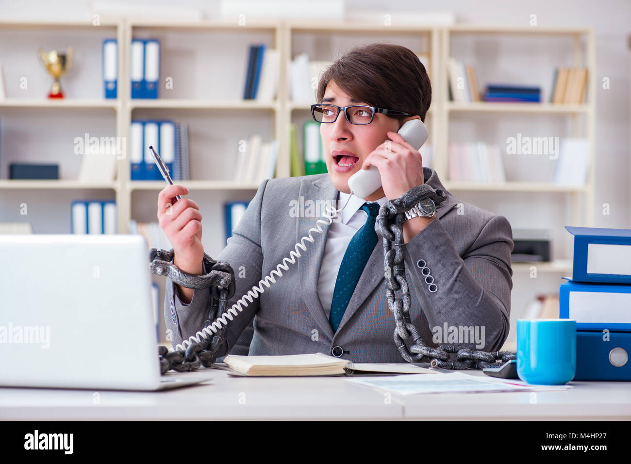 Businessman tied with chains to his work Stock Photo - Alamy