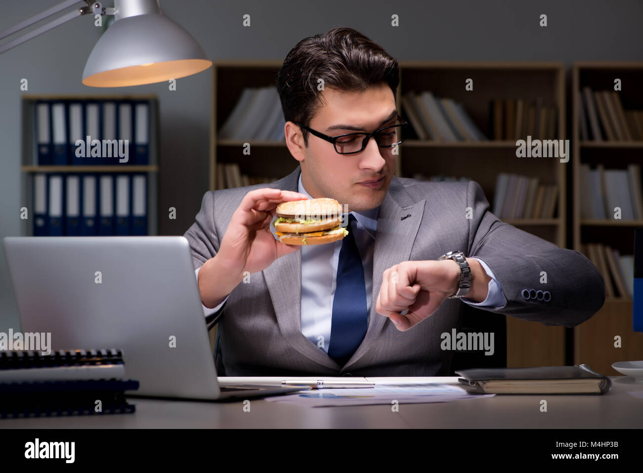 Businessman late at night eating a burger Stock Photo - Alamy