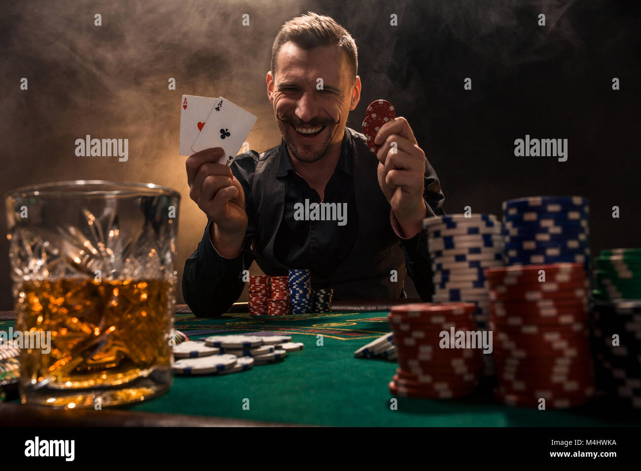 Handsome poker player with two aces in his hands and chips sitting at ...