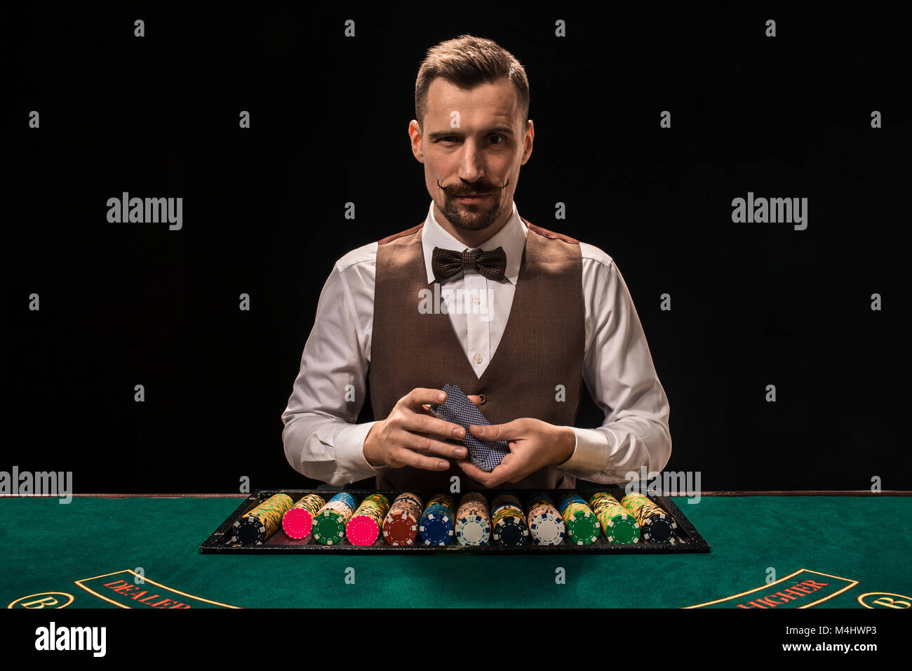 Portrait of a croupier is holding playing cards, gambling chips on ...