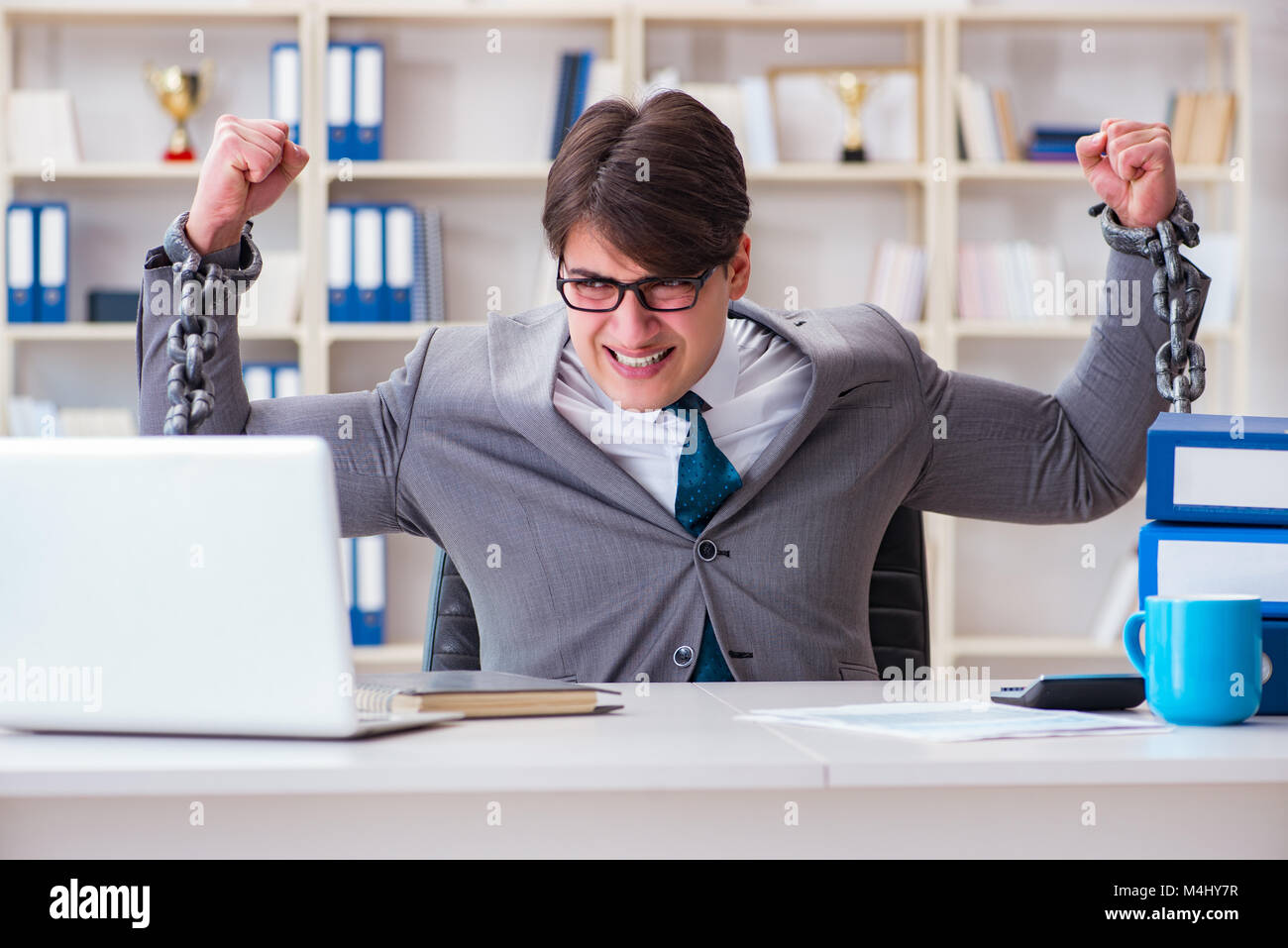 Businessman tied with chains to his work Stock Photo - Alamy