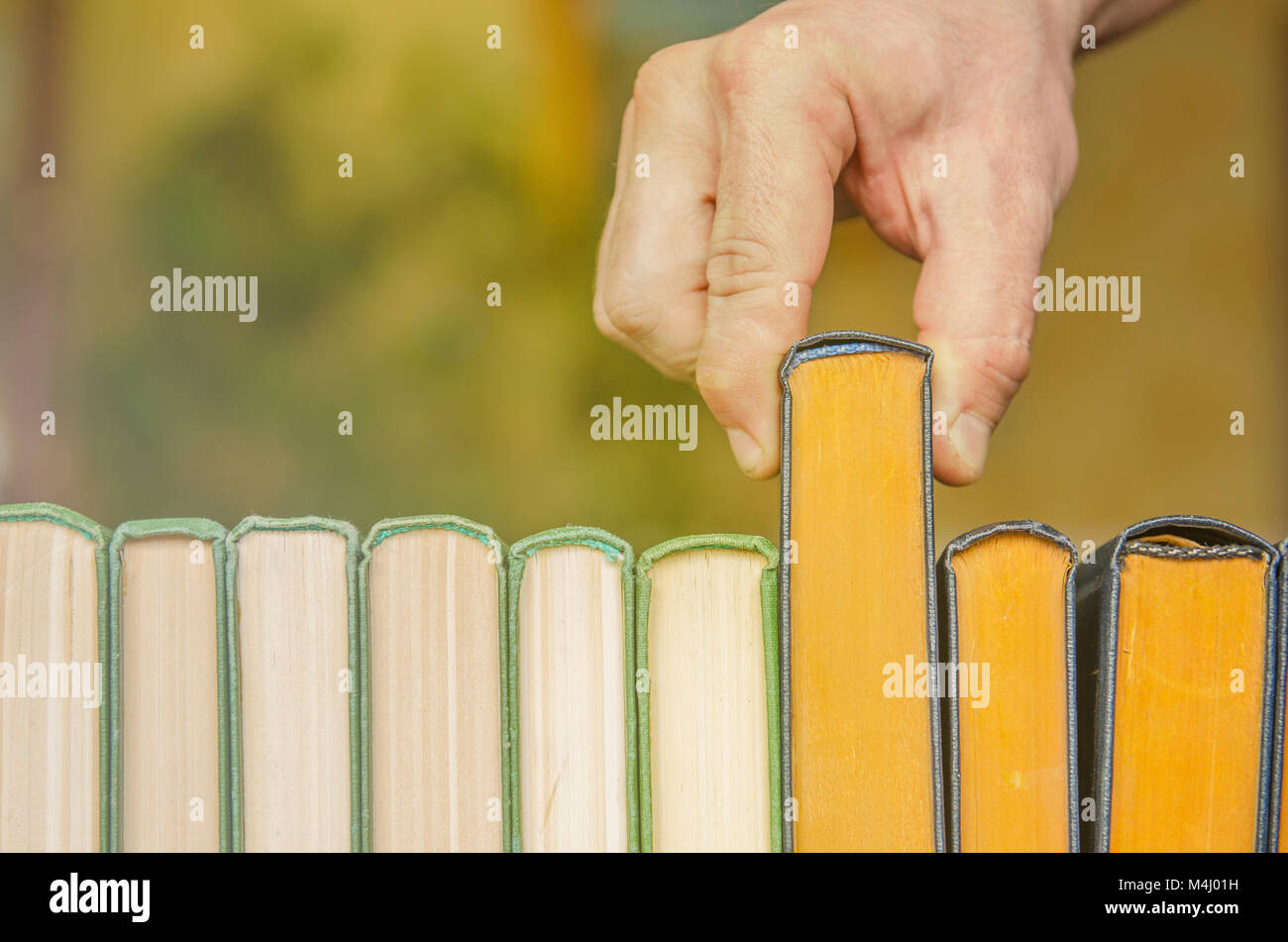 a man's hand pulls a book out of the shelf close-up. education concept ...