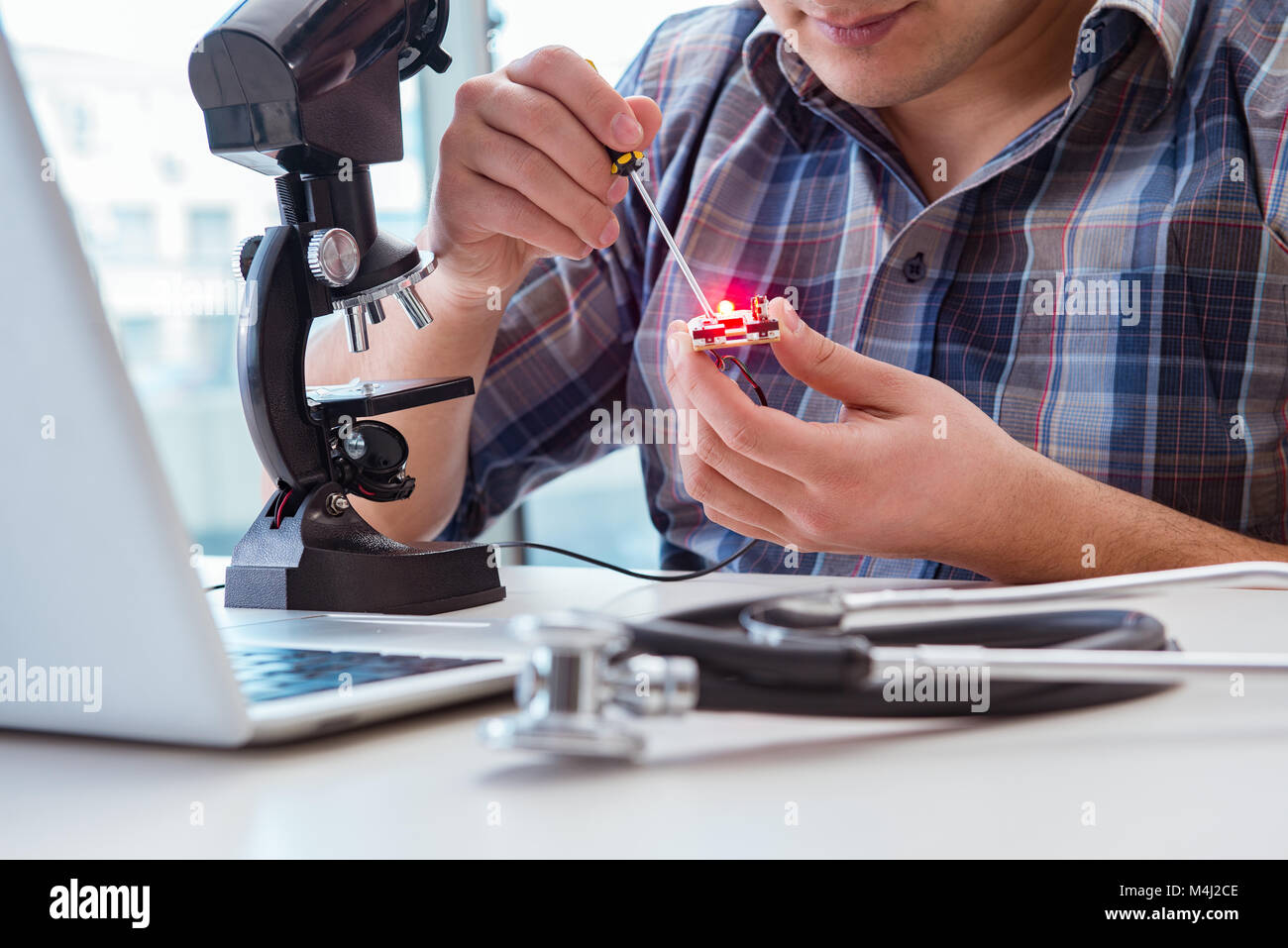 High precision engineering with man working with microscope Stock Photo ...