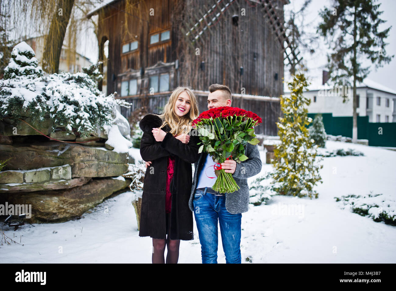 Loving couple in love at winter day with large bouquet of 101 roses ...