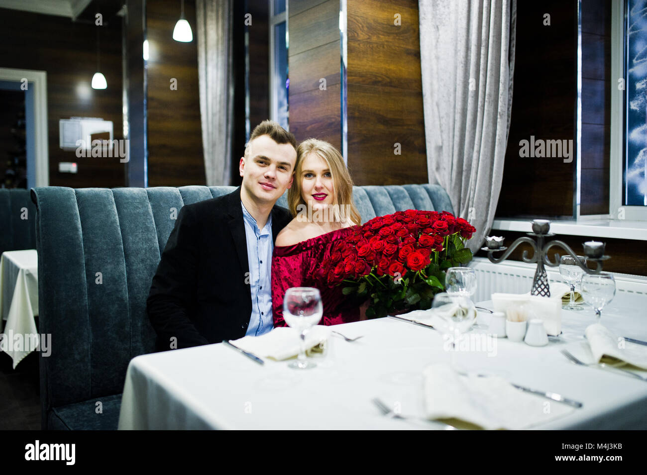 Loving couple in love at restaurant with large bouquet of 101 roses ...