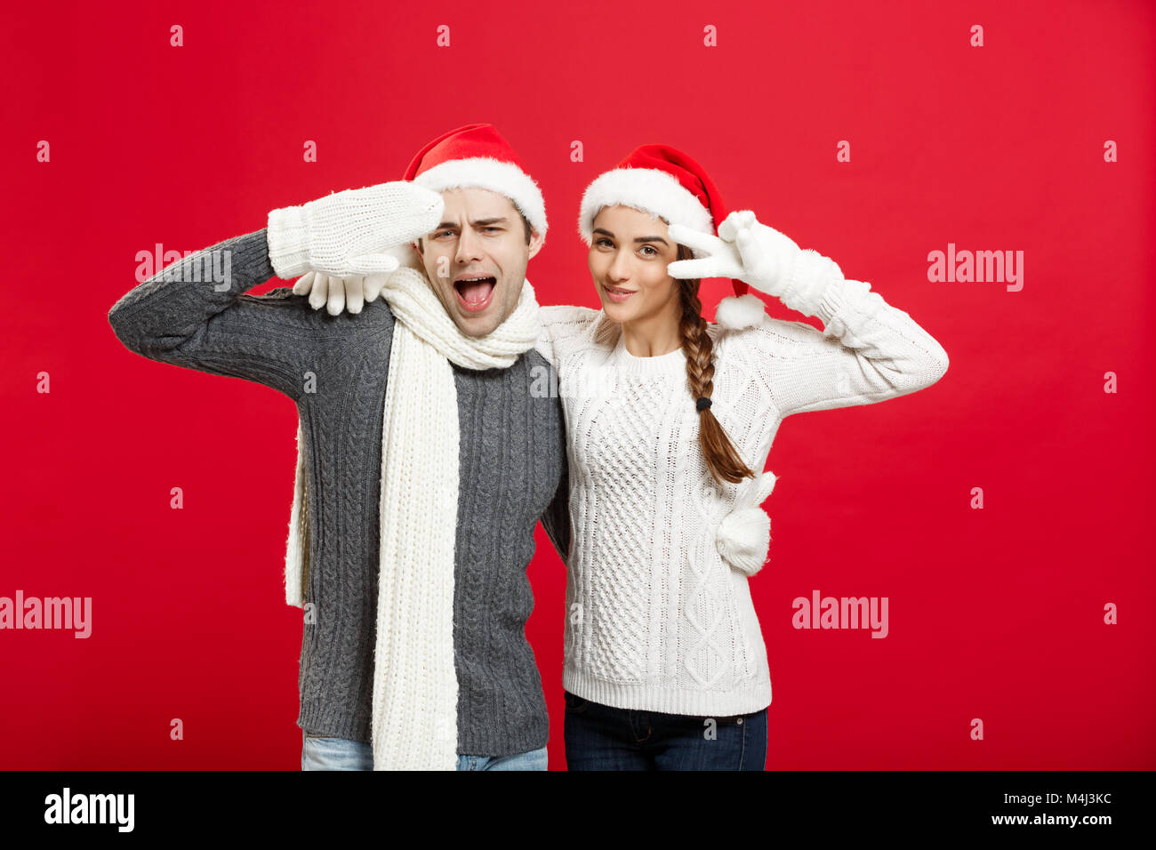 Portrait of a happy young couple posing over red studio background ...