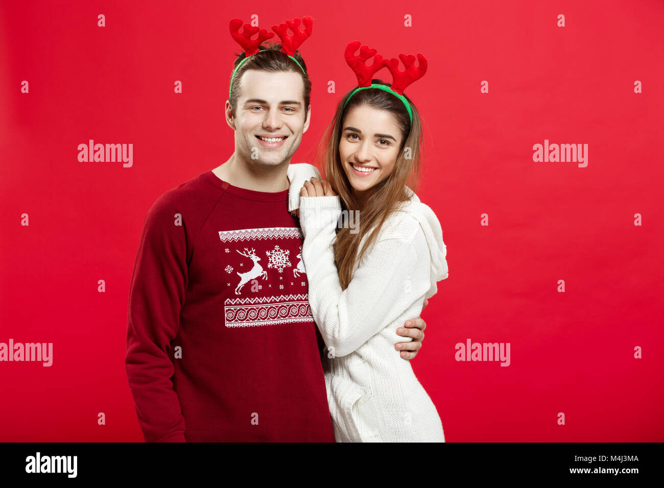Portrait of a happy young couple posing over red studio background ...