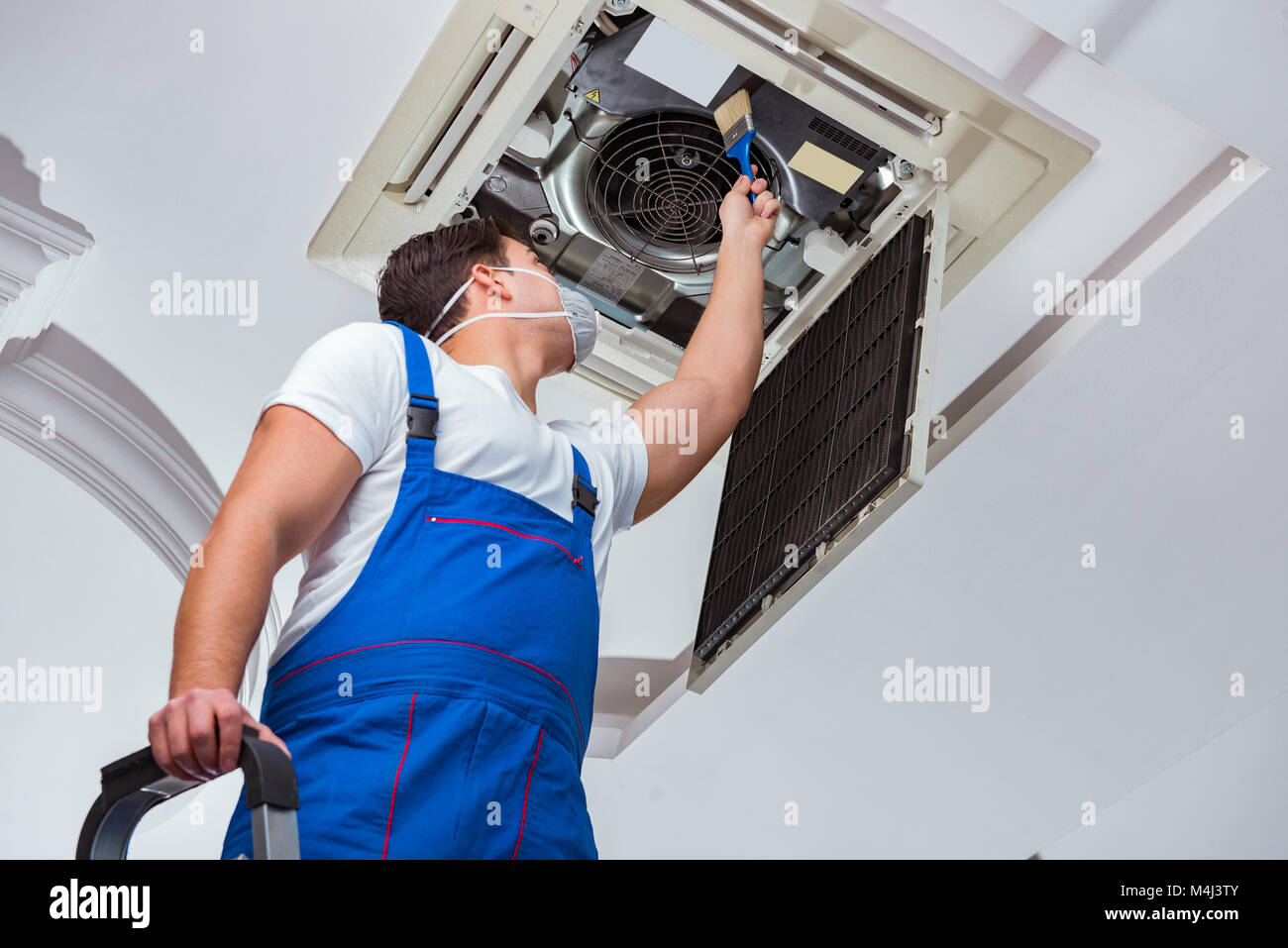 Worker repairing ceiling air conditioning unit Stock Photo - Alamy