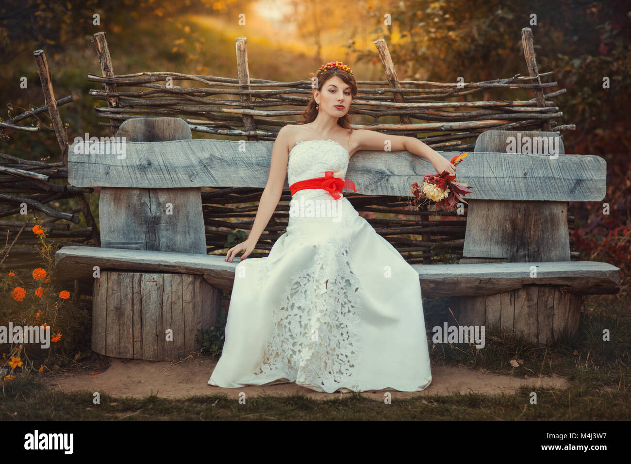 Beautiful bride sitting on an old wooden bench in the autumn park Stock ...