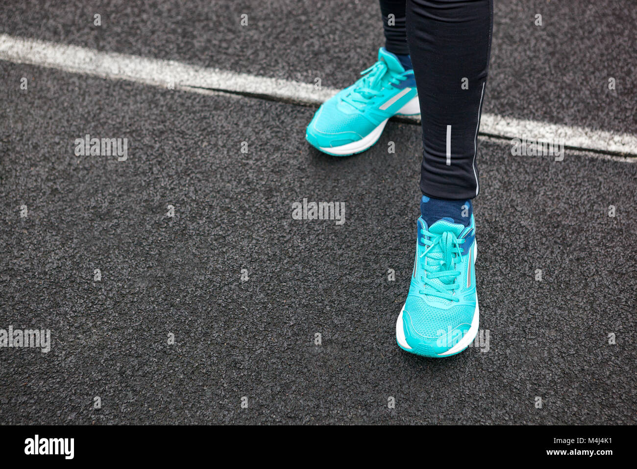 Woman's legs in blue colored running shoes standing on asphalt Stock ...