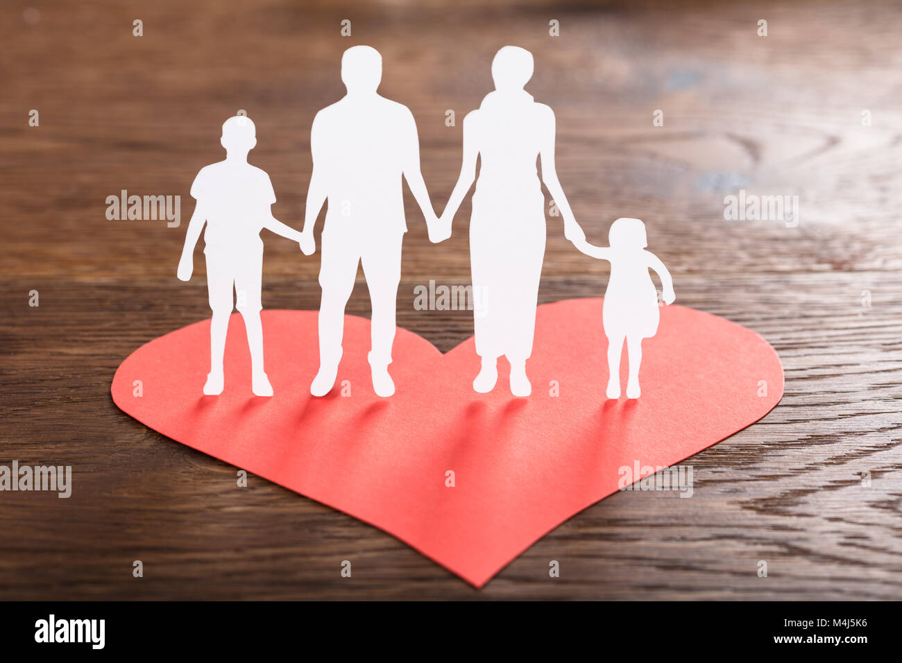 Close-up Of A Family Cut-out On Red Shape Heart At Wooden Desk Stock ...
