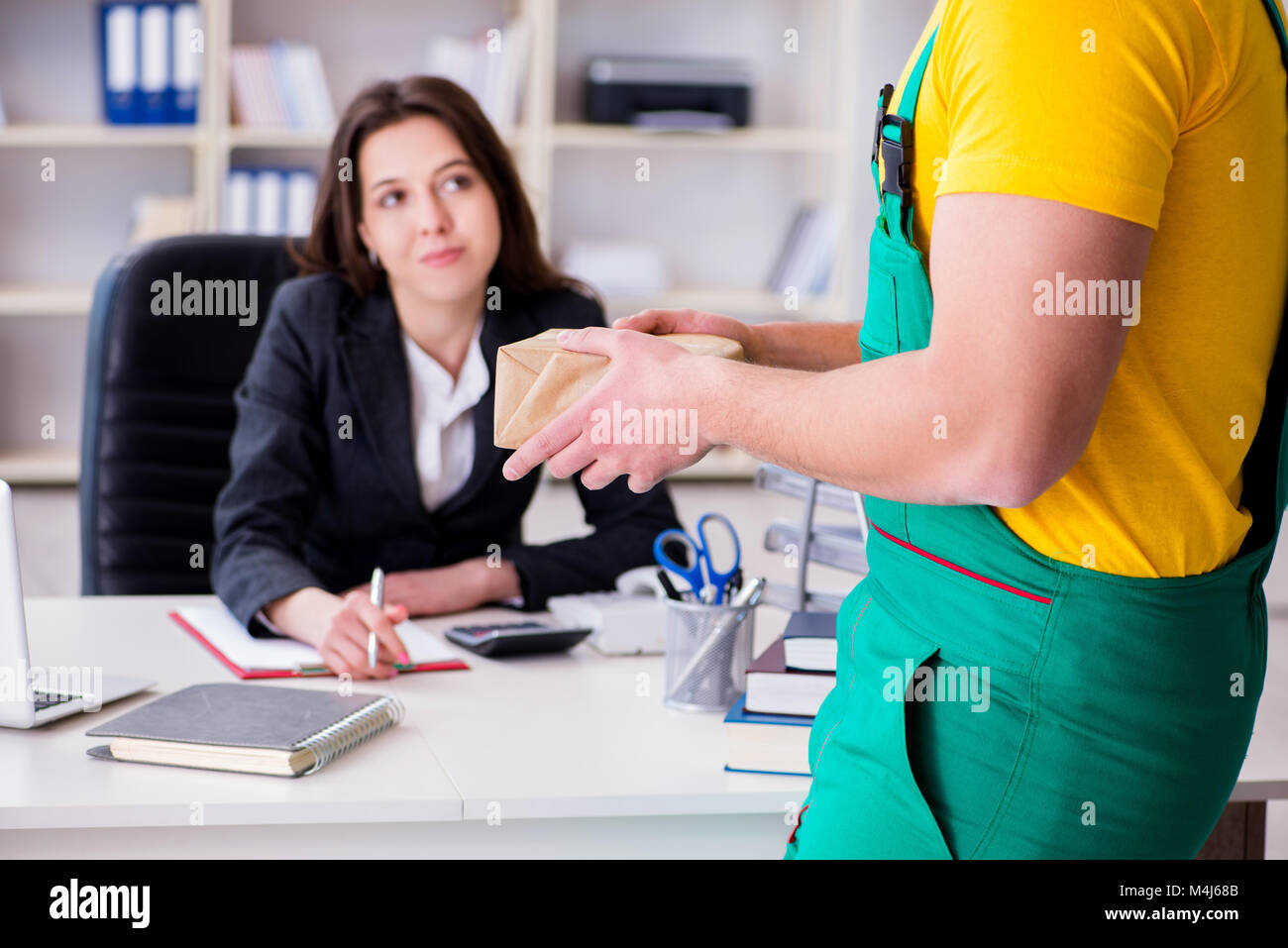 Postman delivering parcel to the office Stock Photo - Alamy