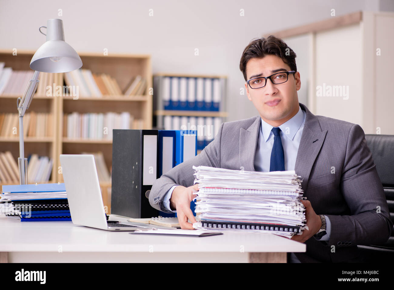 Businessman struggling with stacks of papers Stock Photo - Alamy