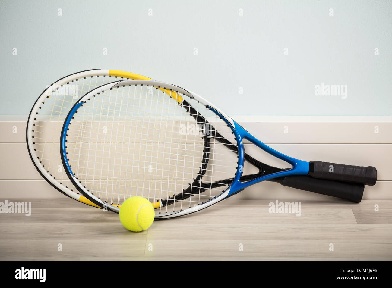 Pair Of Tennis Rackets And A Ball On A Hardwood Floor Stock Photo - Alamy