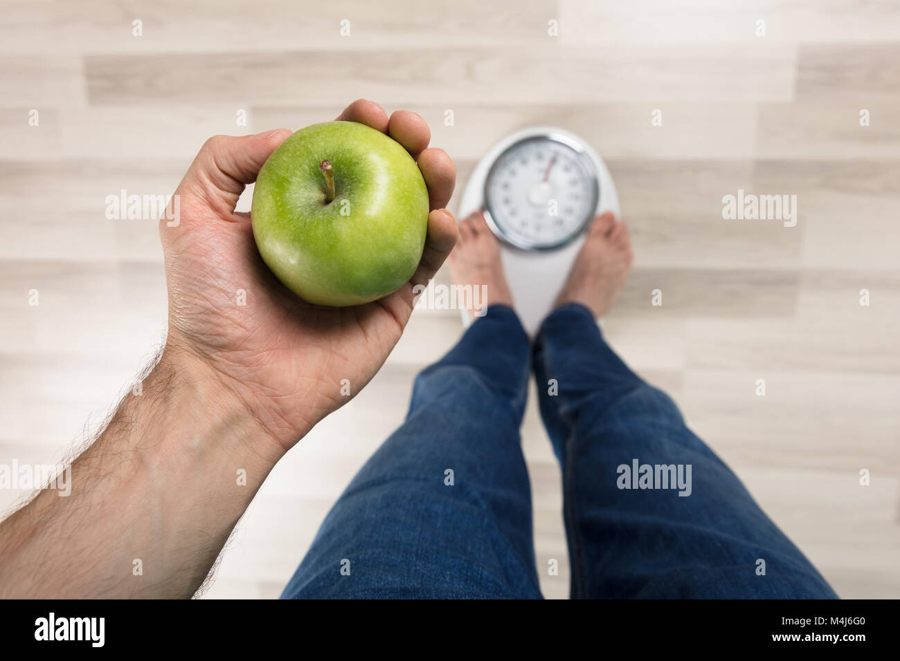 High Angle View Of A Person Measuring Weight While Holding Apple On ...