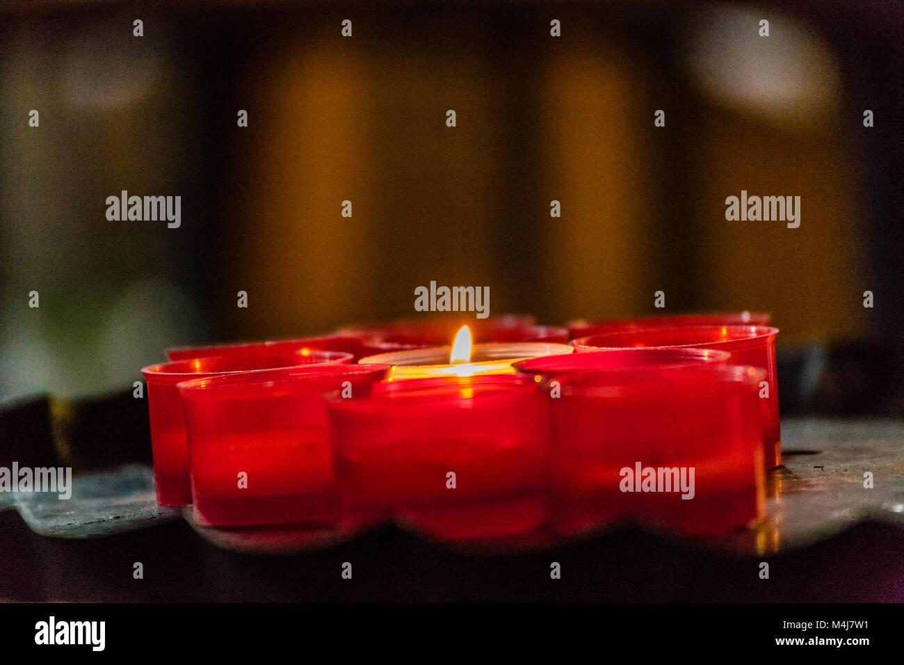 one white candle burning amongst extinguished red ones Stock Photo - Alamy