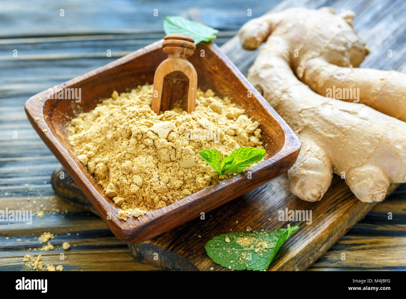 Ground ginger in wooden bowl and ginger root Stock Photo - Alamy