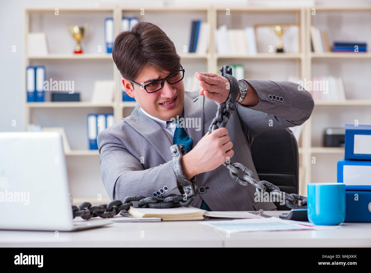 Businessman tied with chains to his work Stock Photo - Alamy