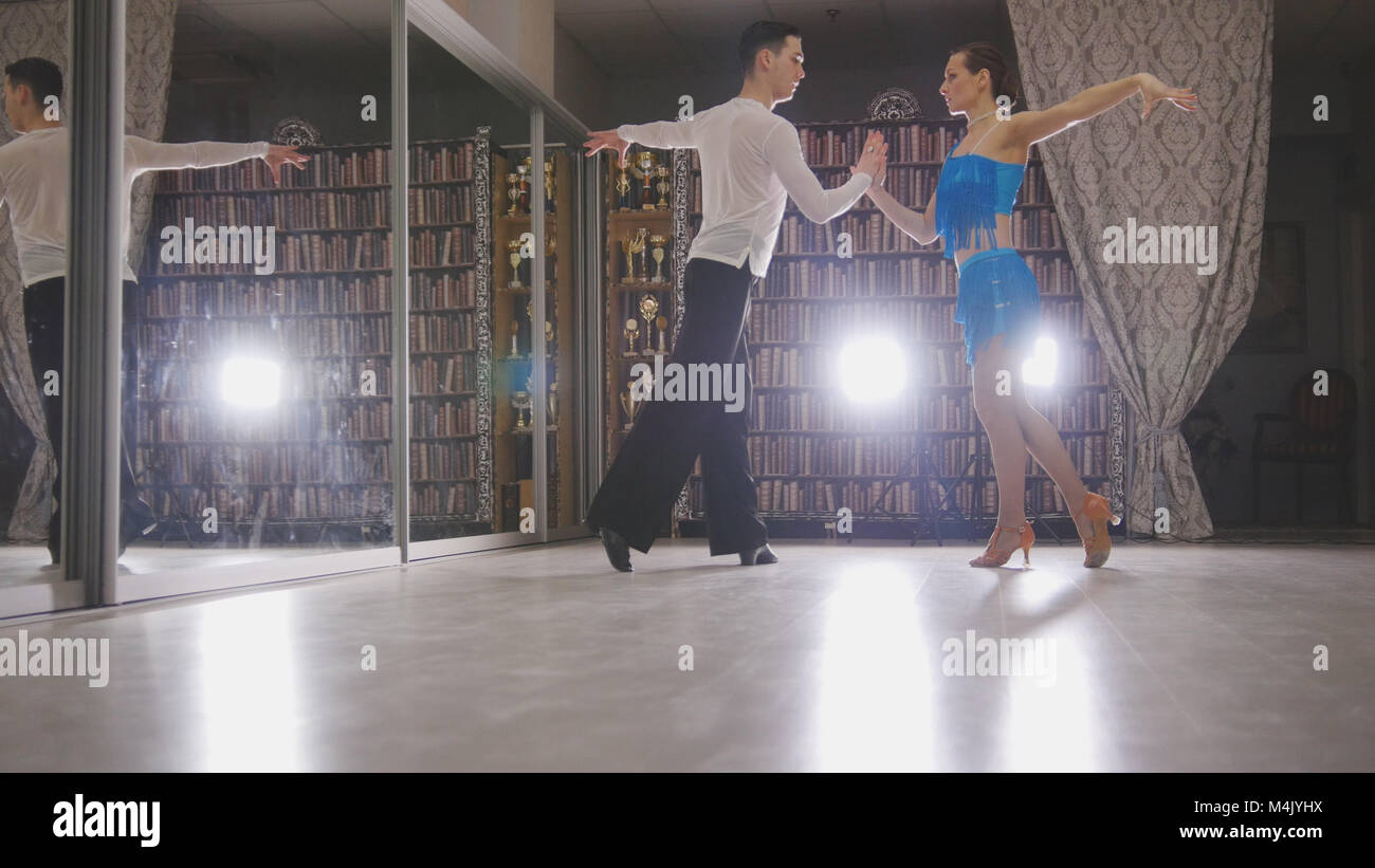 Young beautiful man and woman dancing and rehearsing Latin dance in ...