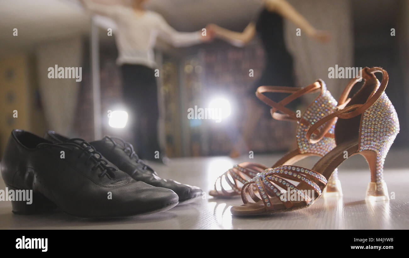 Blurred professional man and woman dancing Latin dance in costumes in studio, two pairs ballroom ...