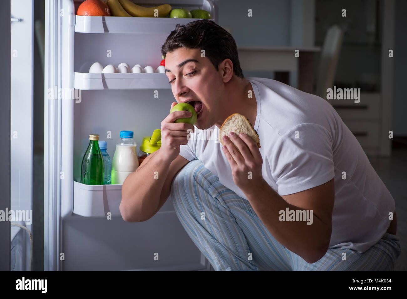 Man at the fridge eating at night Stock Photo - Alamy