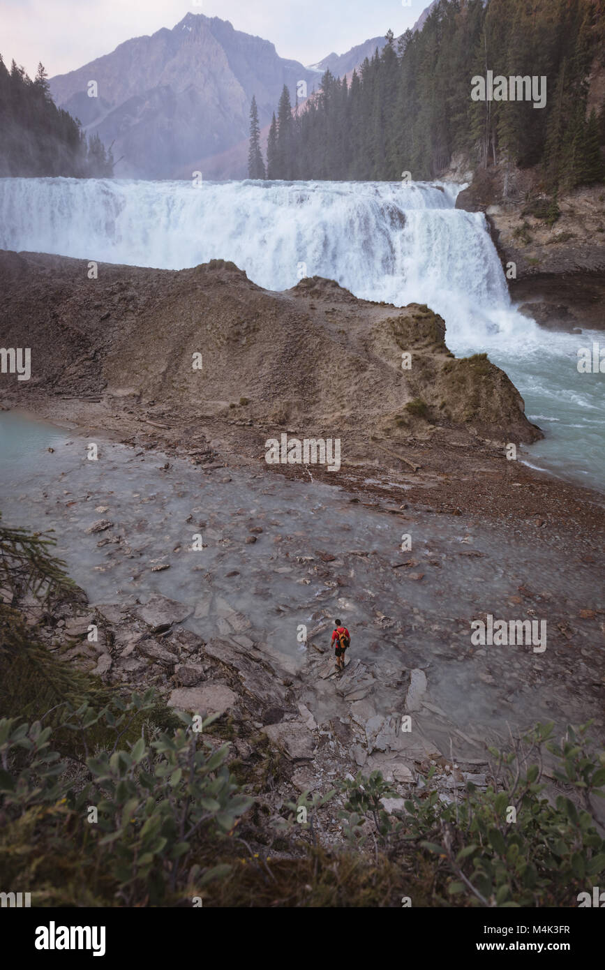 Man standing on stream near waterfall Stock Photo - Alamy