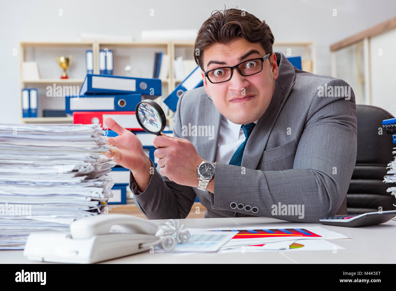 Male businessman with magnifying glass in office Stock Photo - Alamy