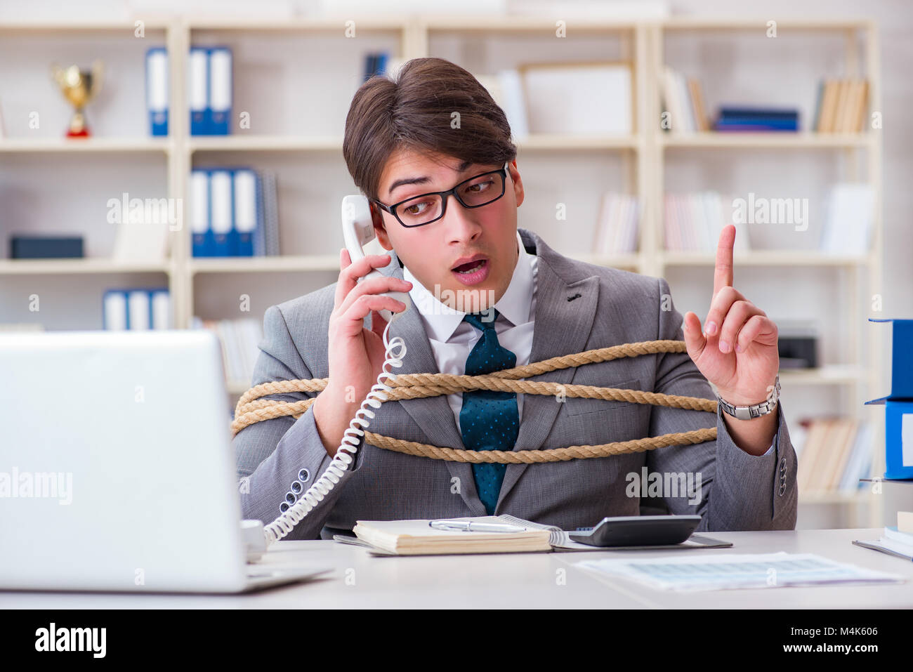 Businessman tied up with rope in office Stock Photo - Alamy