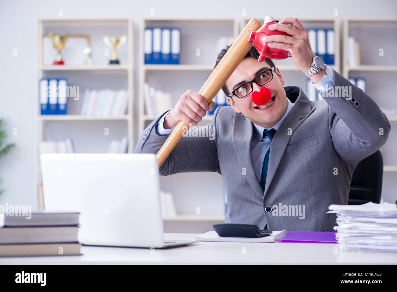 Clown businessman with a baseball bat and a piggy bank Stock Photo - Alamy
