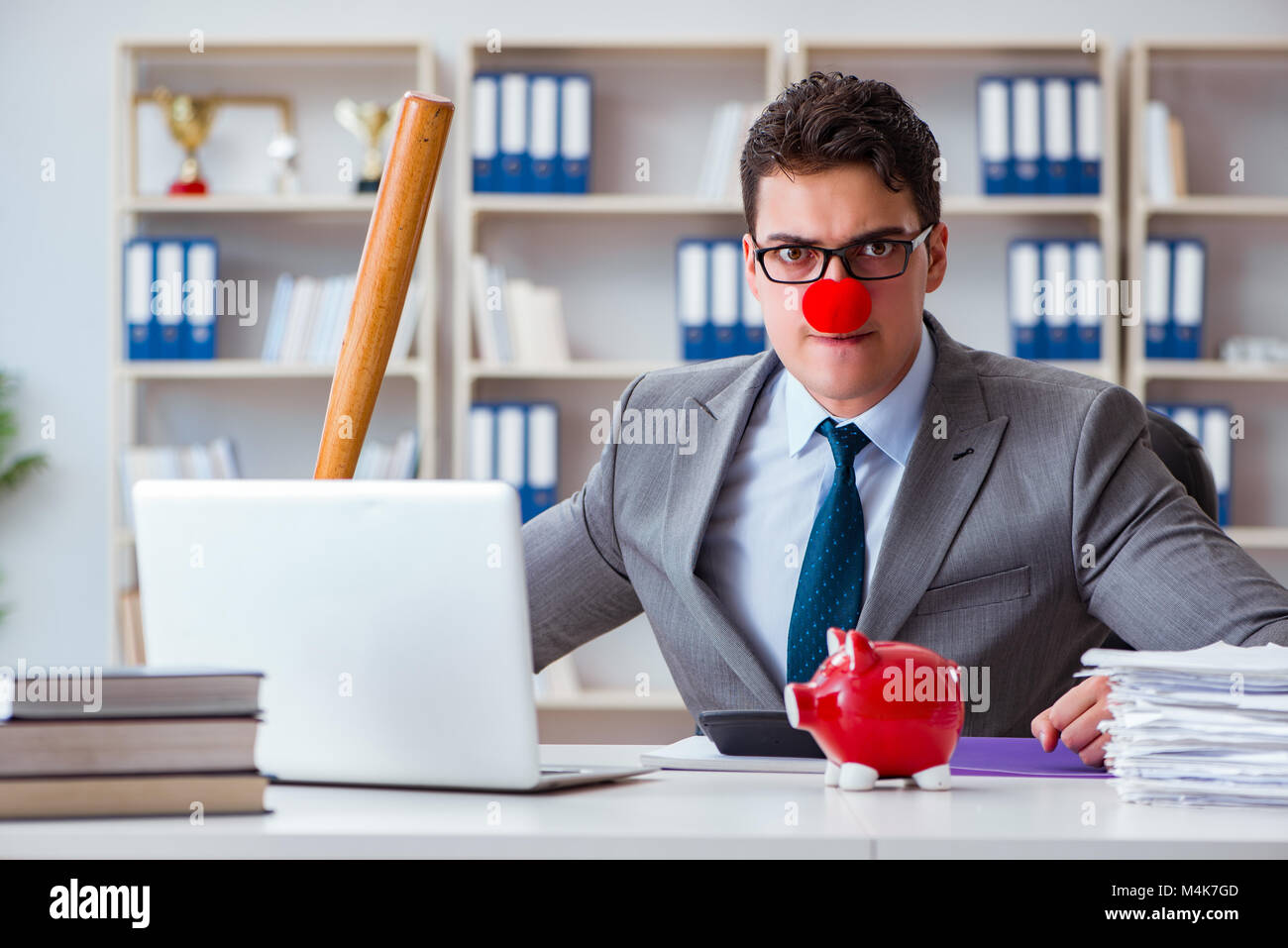 Clown businessman with a baseball bat and a piggy bank Stock Photo - Alamy
