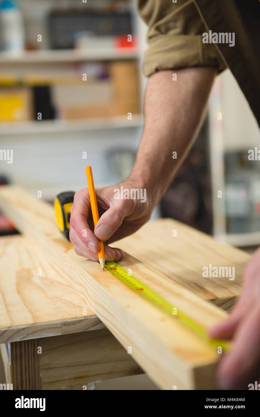 Male carpenter measuring and marking wood in workshop Stock Photo - Alamy