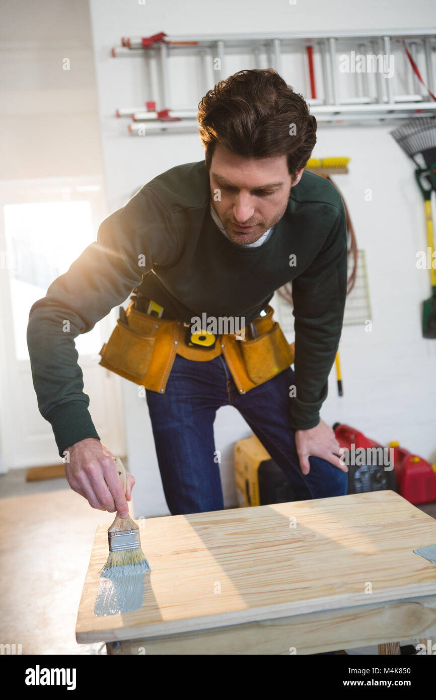 Male carpenter painting a table Stock Photo - Alamy