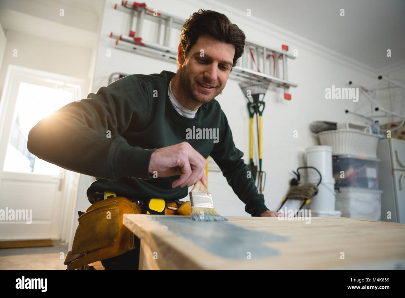 Male carpenter painting a table Stock Photo - Alamy