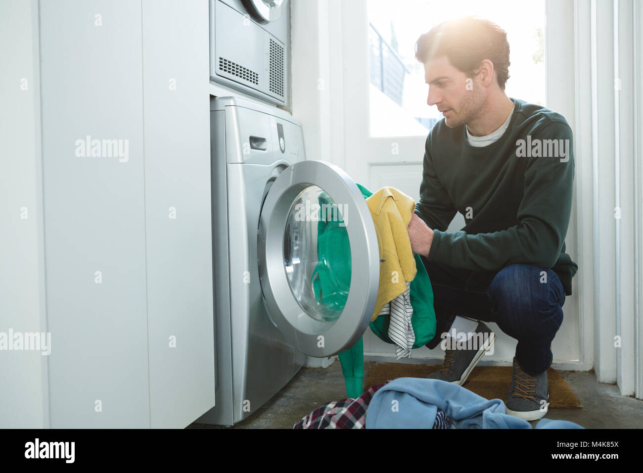 Man putting clothes in washing machine Stock Photo - Alamy