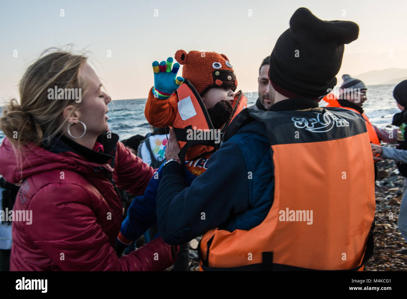 Volunteers help take a very young child out of the dinghy where he has ...