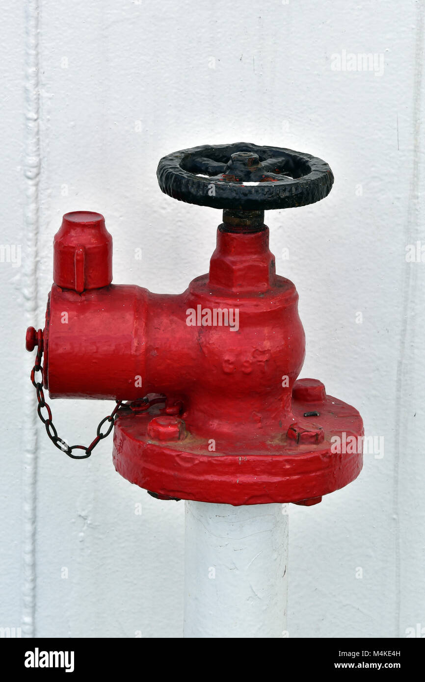 A red painted fire hydrant valve with a black wheel for shutting and ...