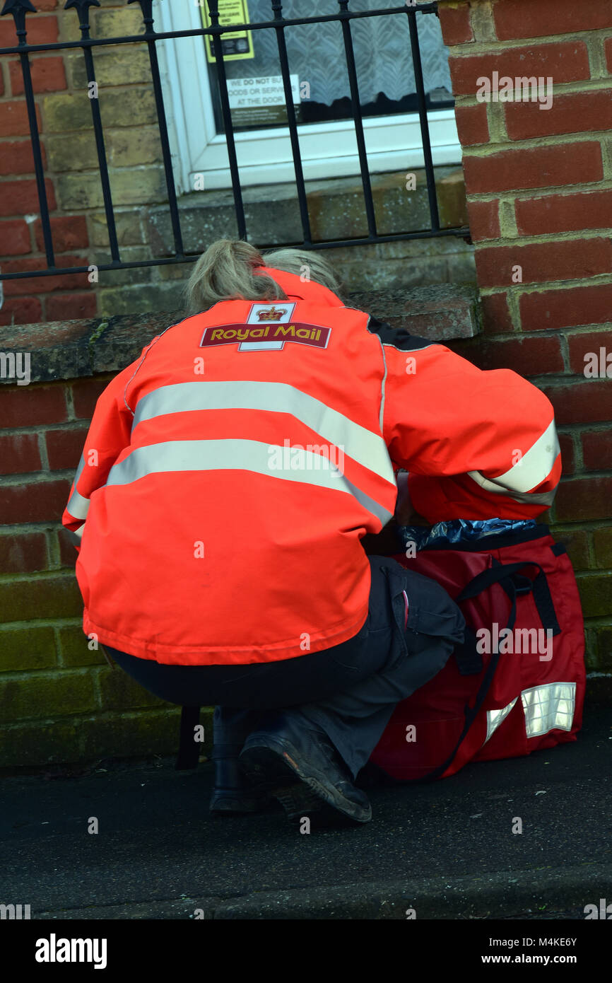 a postal worker woman bending over to look into a mail sack or bag ...