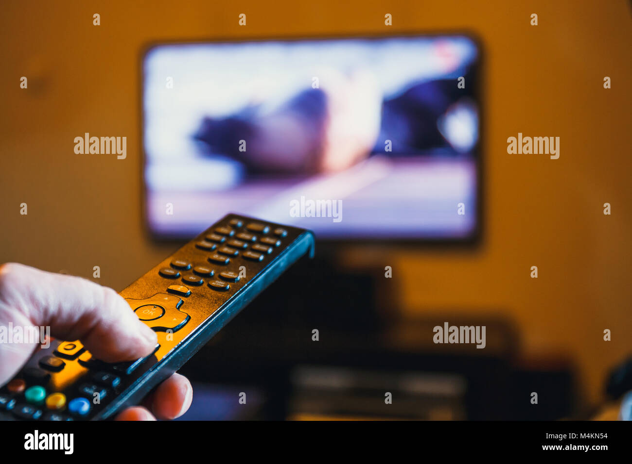 Hand holding TV remote control and presses the button Stock Photo - Alamy