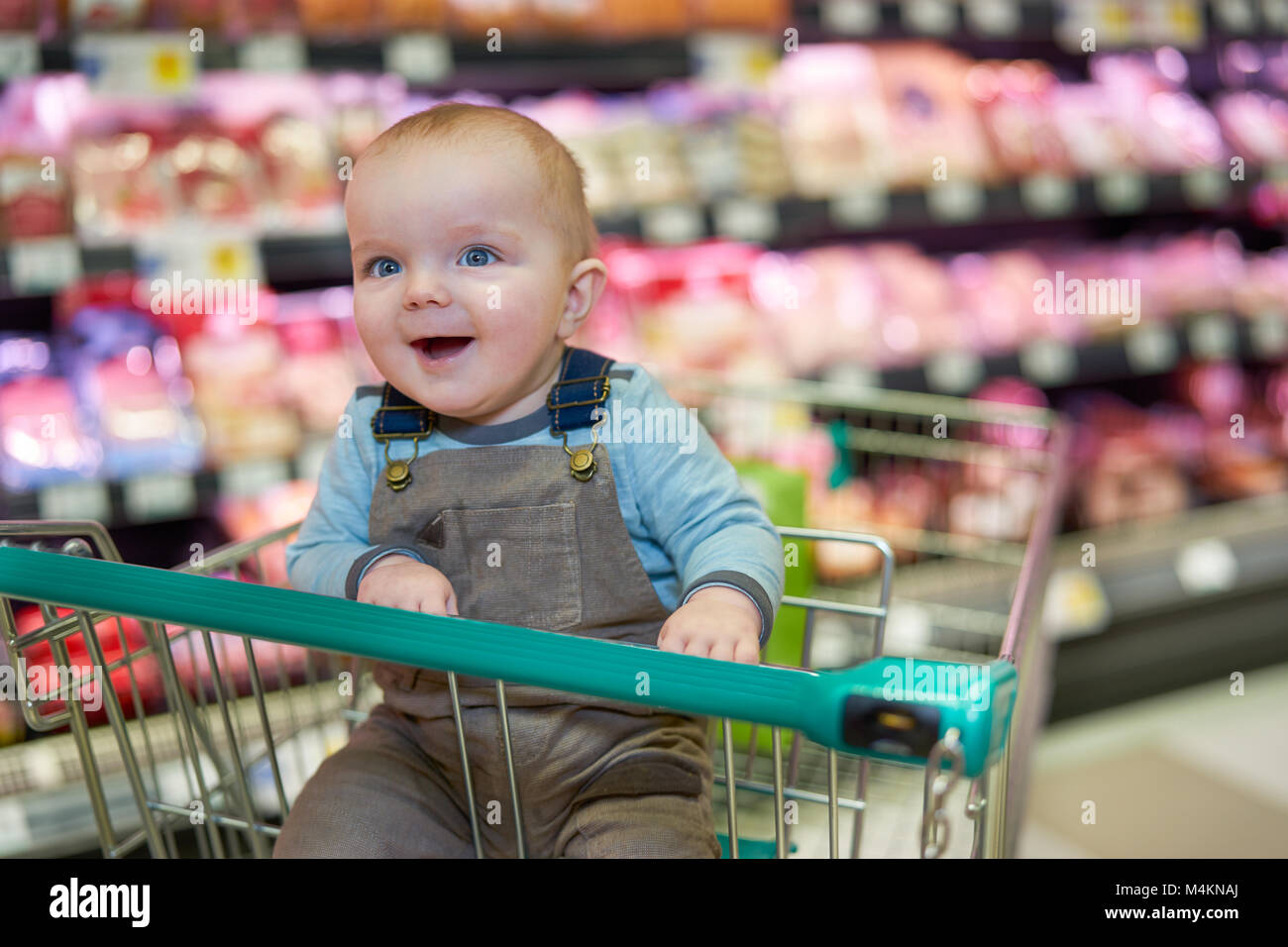 Cute and smiling toddler sitting in trolley in supermarket Stock Photo ...